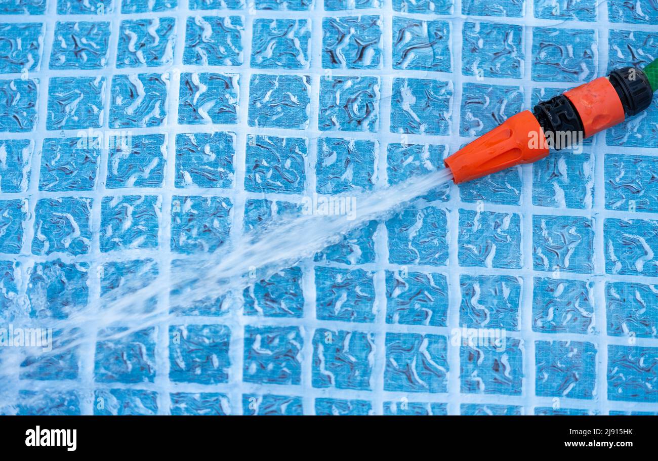Pouring water into the garden pool. Water jets from a garden hose. Blue ...