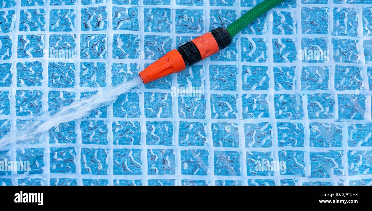 Pouring water into the garden pool. Water jets from a garden hose. Blue ...