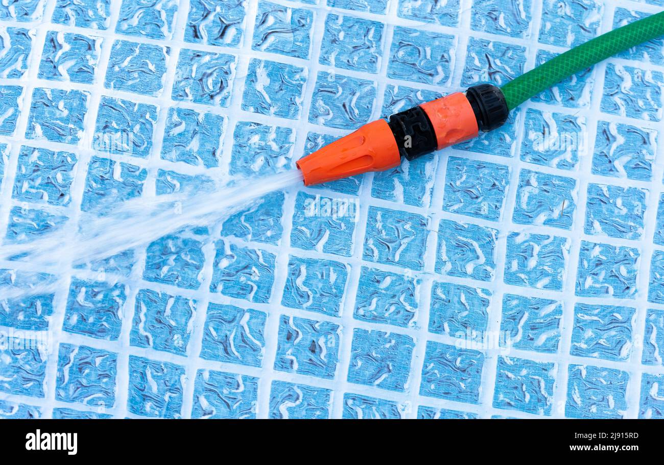 Pouring water into the garden pool. Water jets from a garden hose. Blue ...