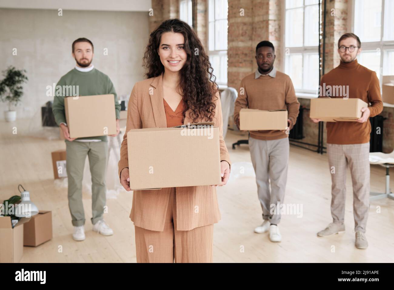 Portrait of smiling attractive business owner and her employee carrying ...