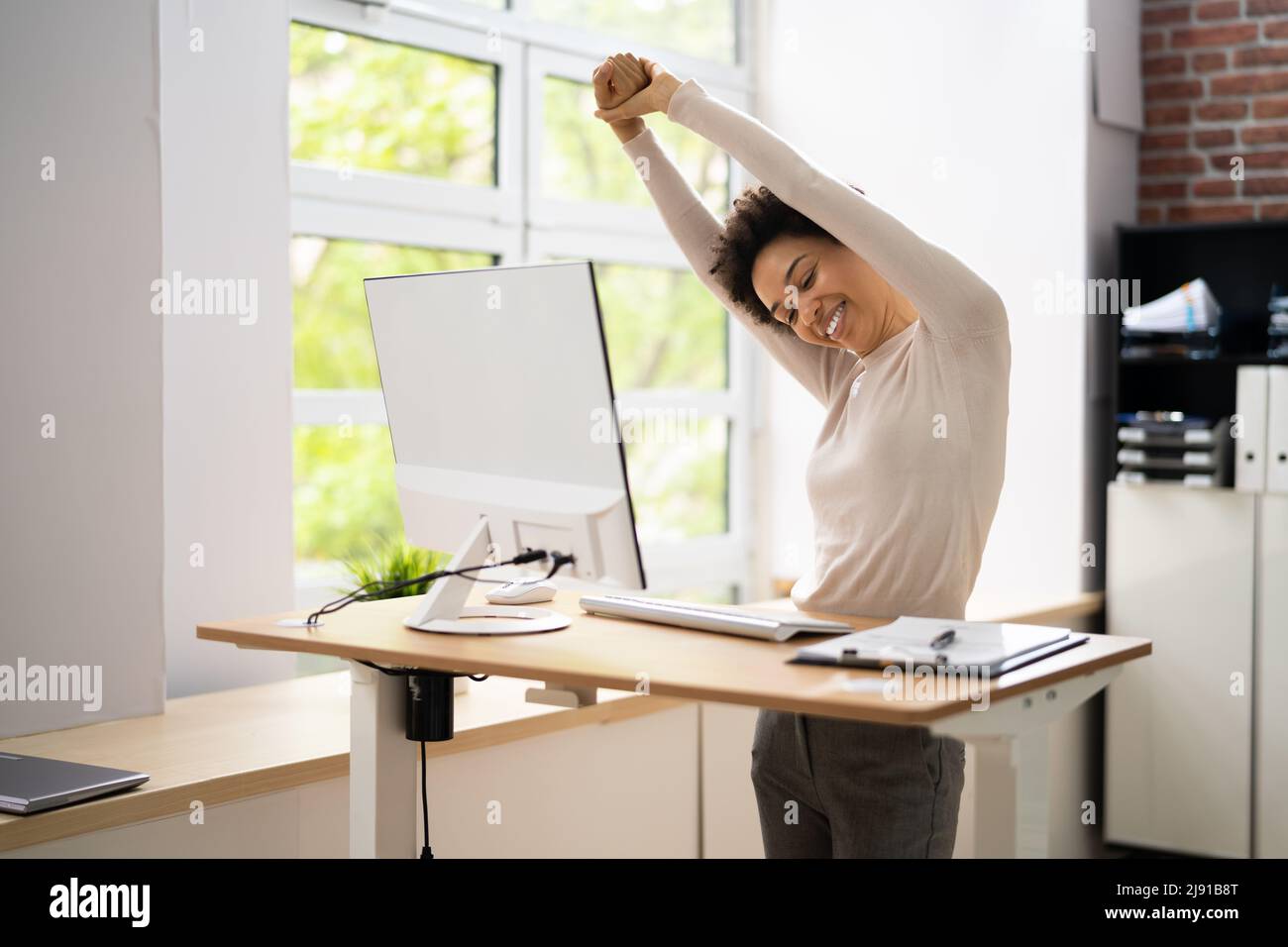 Worker Stretch Exercise At Stand Desk In Office Stock Photo - Alamy