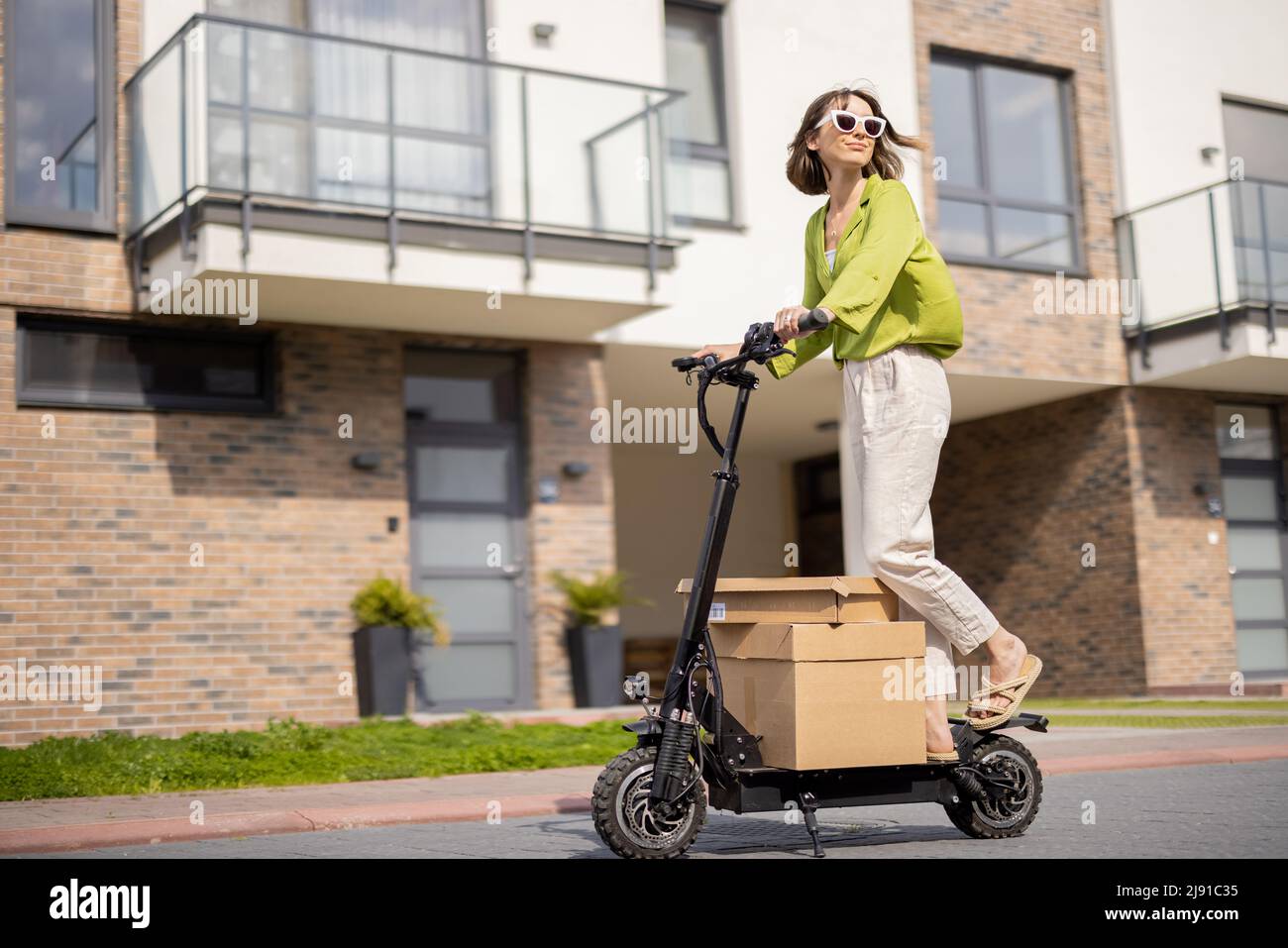 Woman driving electric scooter with cardboard packages Stock Photo - Alamy