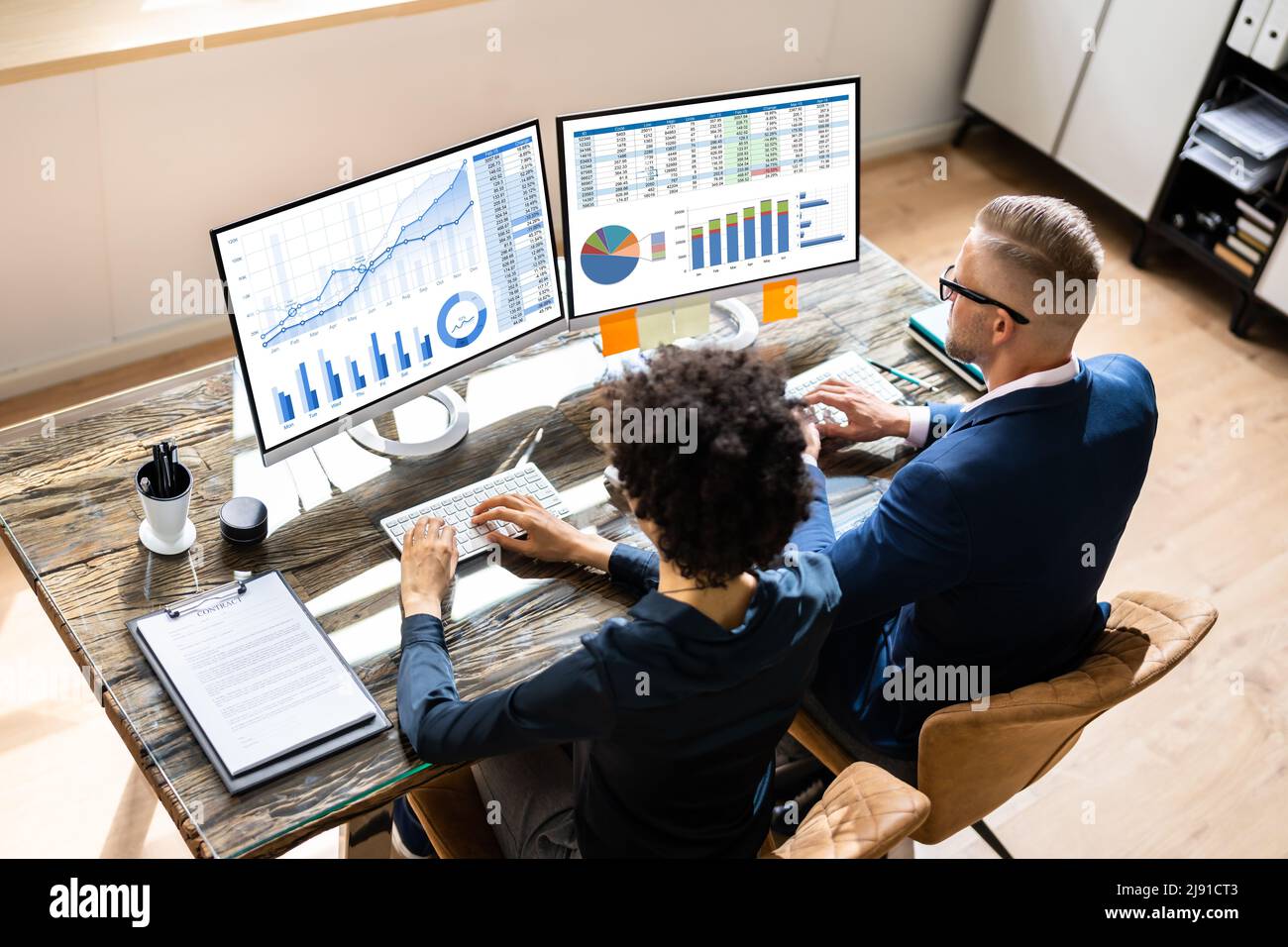 Side View Of Male And Female Stock Market Broker Analyzing Graphs On ...