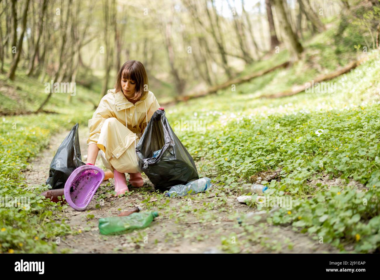 Woman collecting scattered plastic garbage in the woods Stock Photo - Alamy