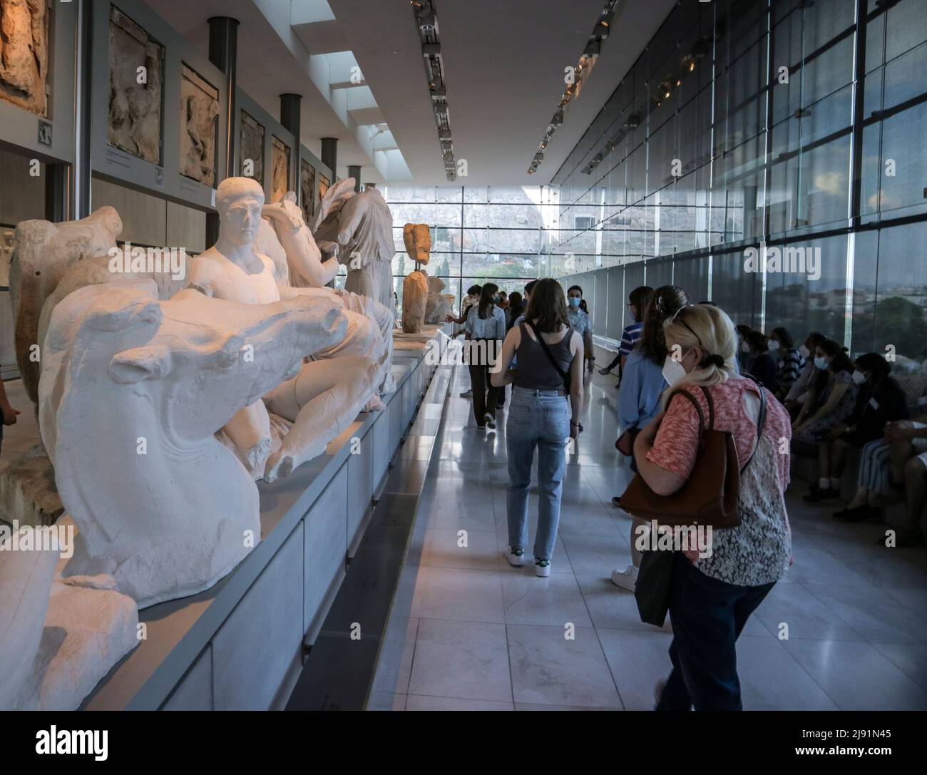 Visistors pass by the plaster copies of the Elgin marbles in the Acropolis museum. Tourists and ...