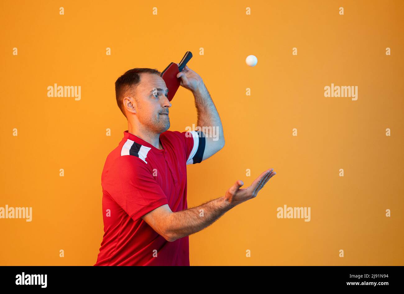 Man plays table tennis on yellow studio background. Professional player ...