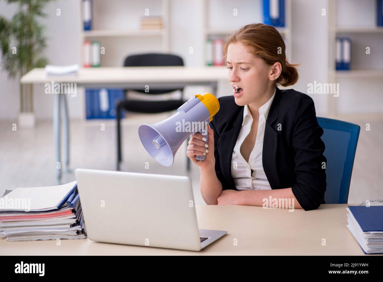 Female employee holding megaphone at workplace Stock Photo - Alamy