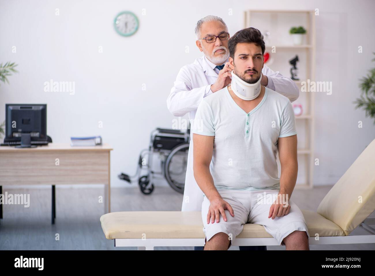 Young neck injured patient visiting old doctor Stock Photo - Alamy