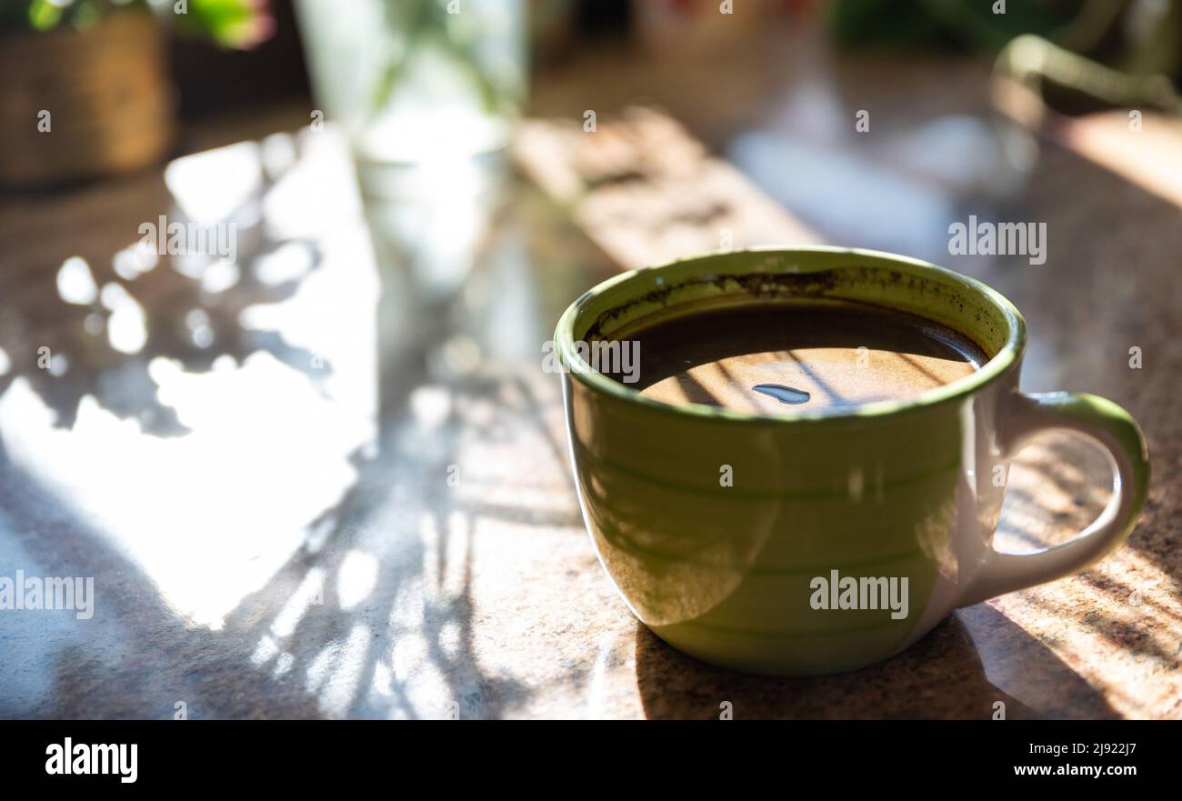 A cup of coffee. The rays of the morning sun shining on a cup of black ...
