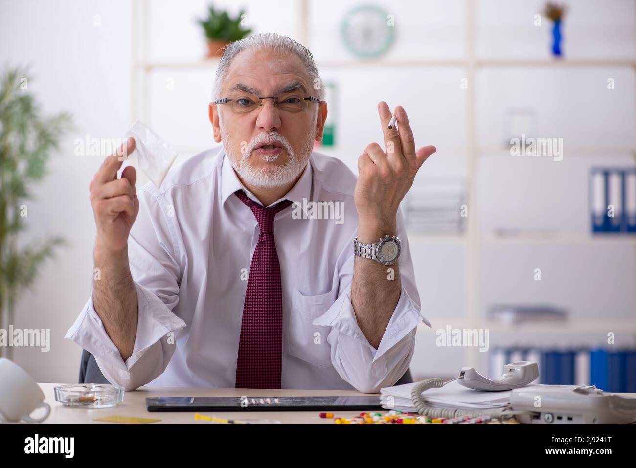 Old male drug addicted employee sitting at workplace Stock Photo - Alamy
