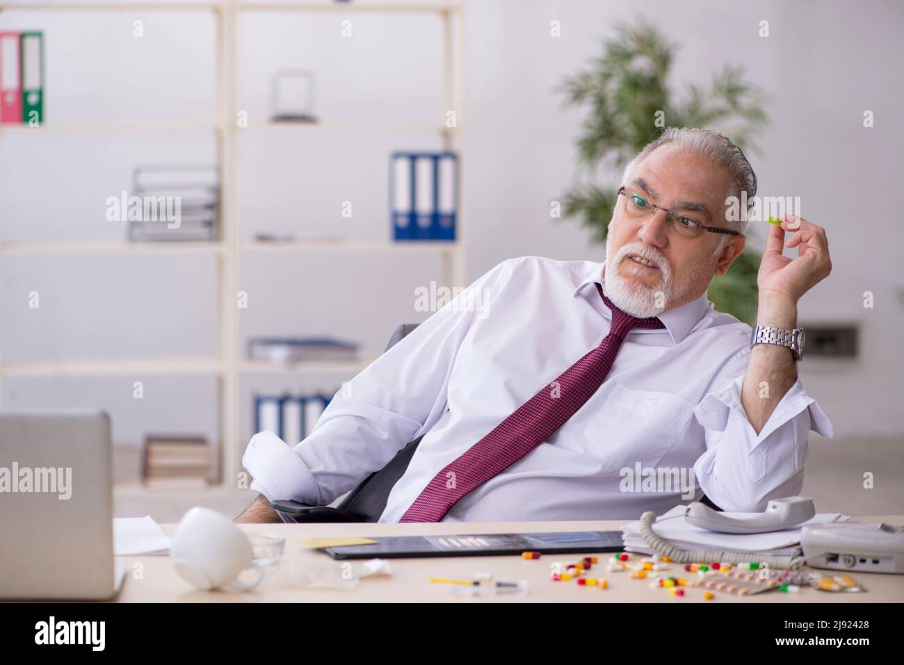 Old male drug addicted employee sitting at workplace Stock Photo - Alamy
