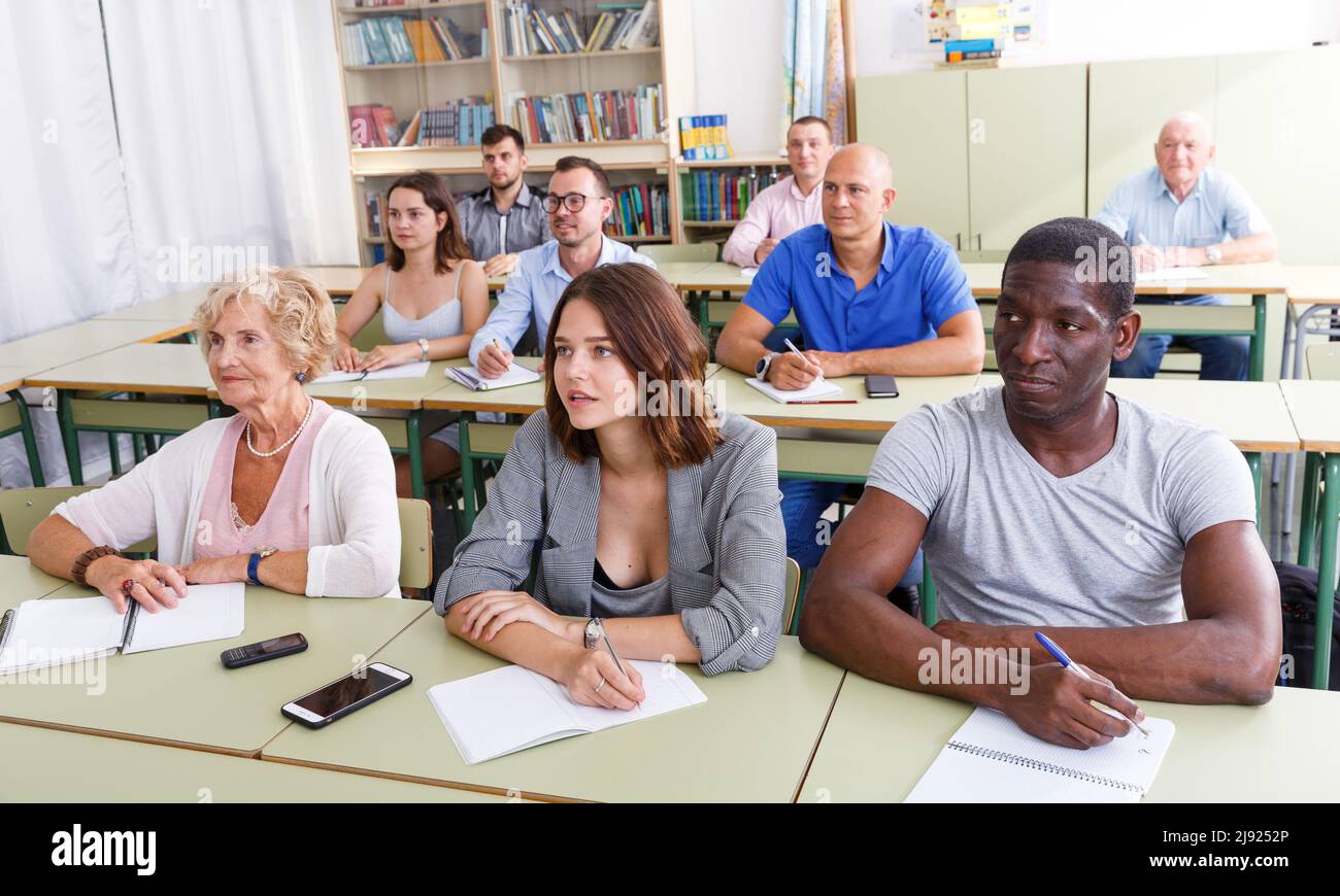 Glad students mixed age listening task for exam Stock Photo - Alamy