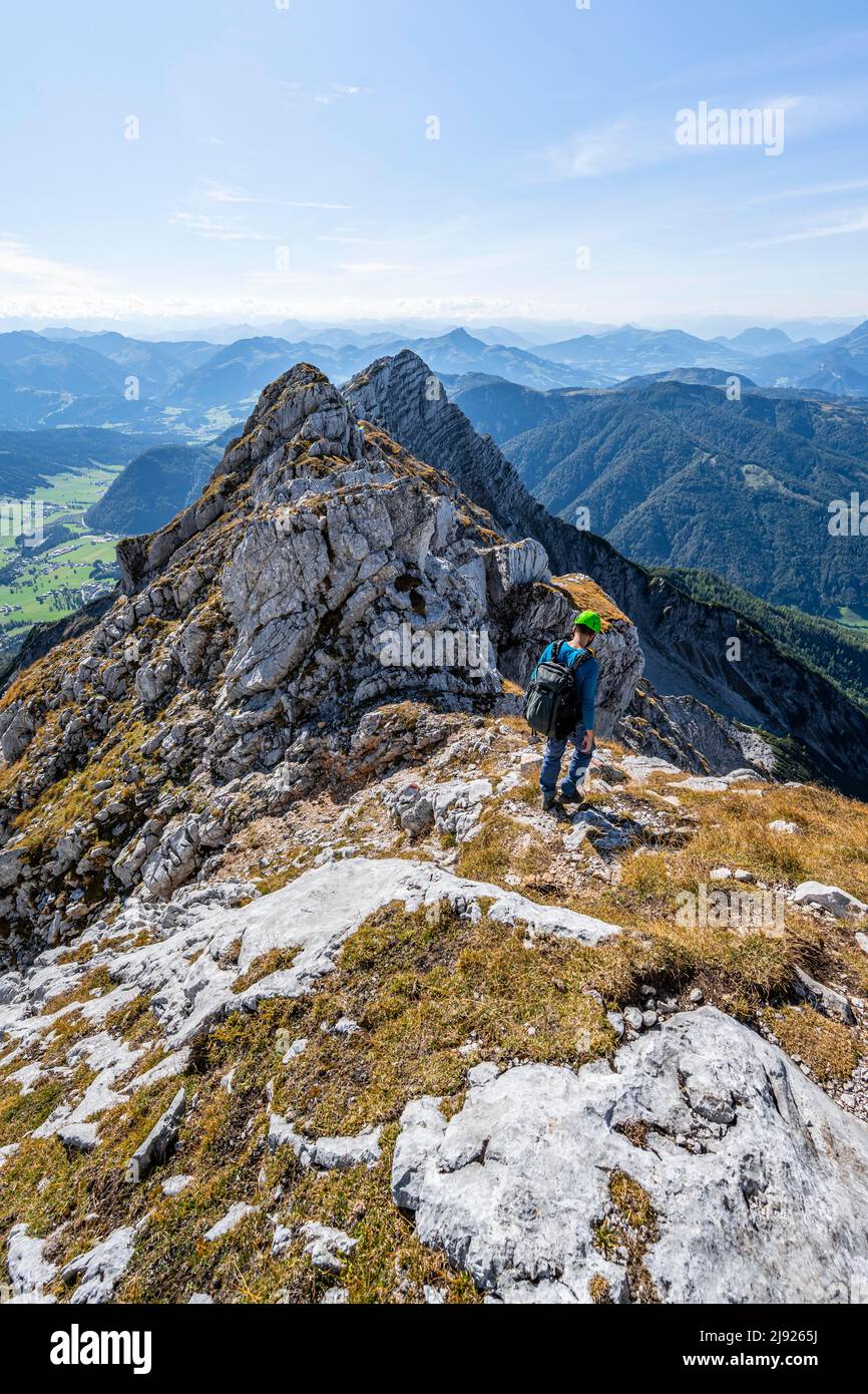 Hiker with climbing helmet, on hiking trail at a ridge, view of ...