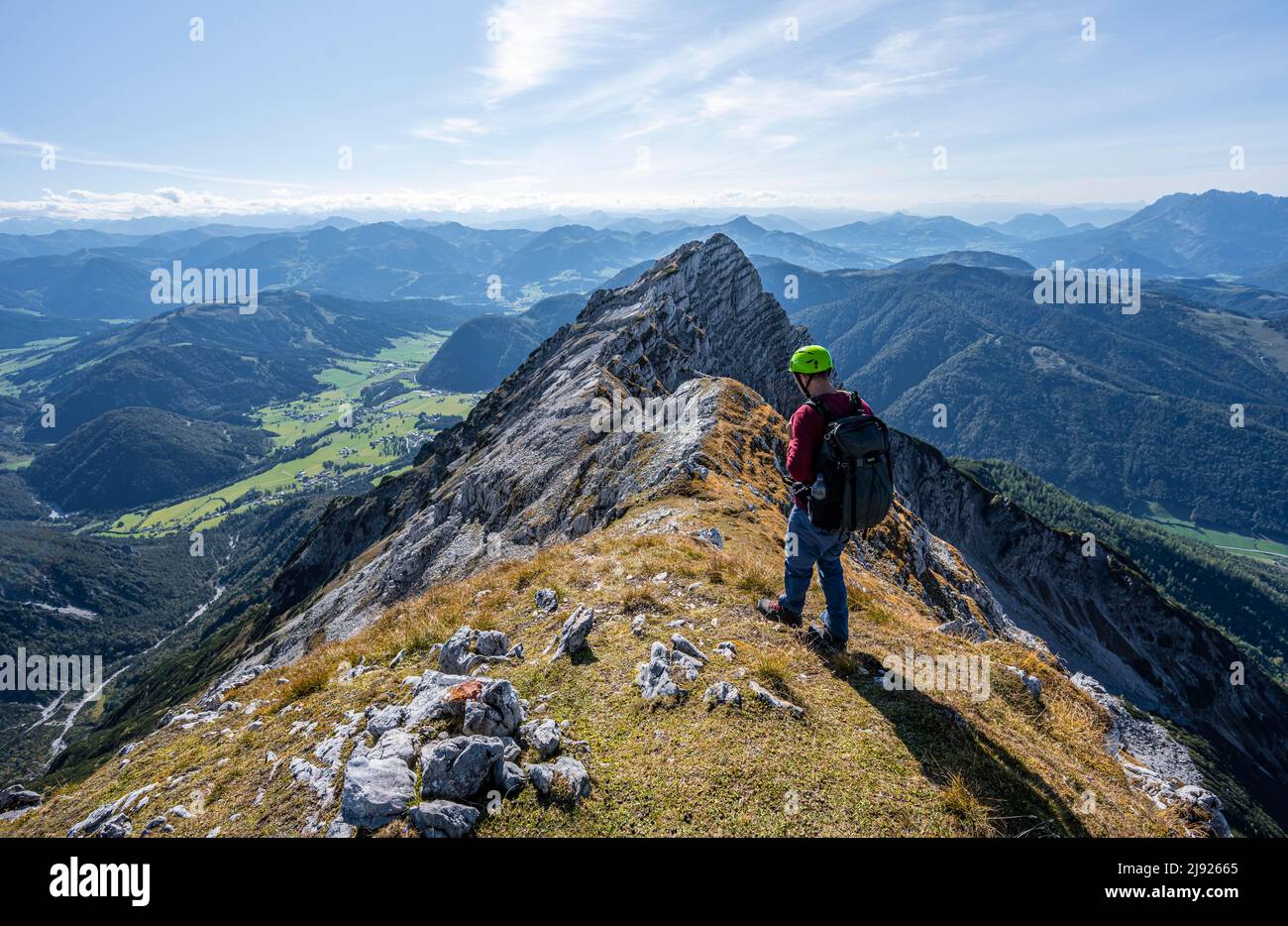 Hiker with climbing helmet, on hiking trail at a ridge, view of ...