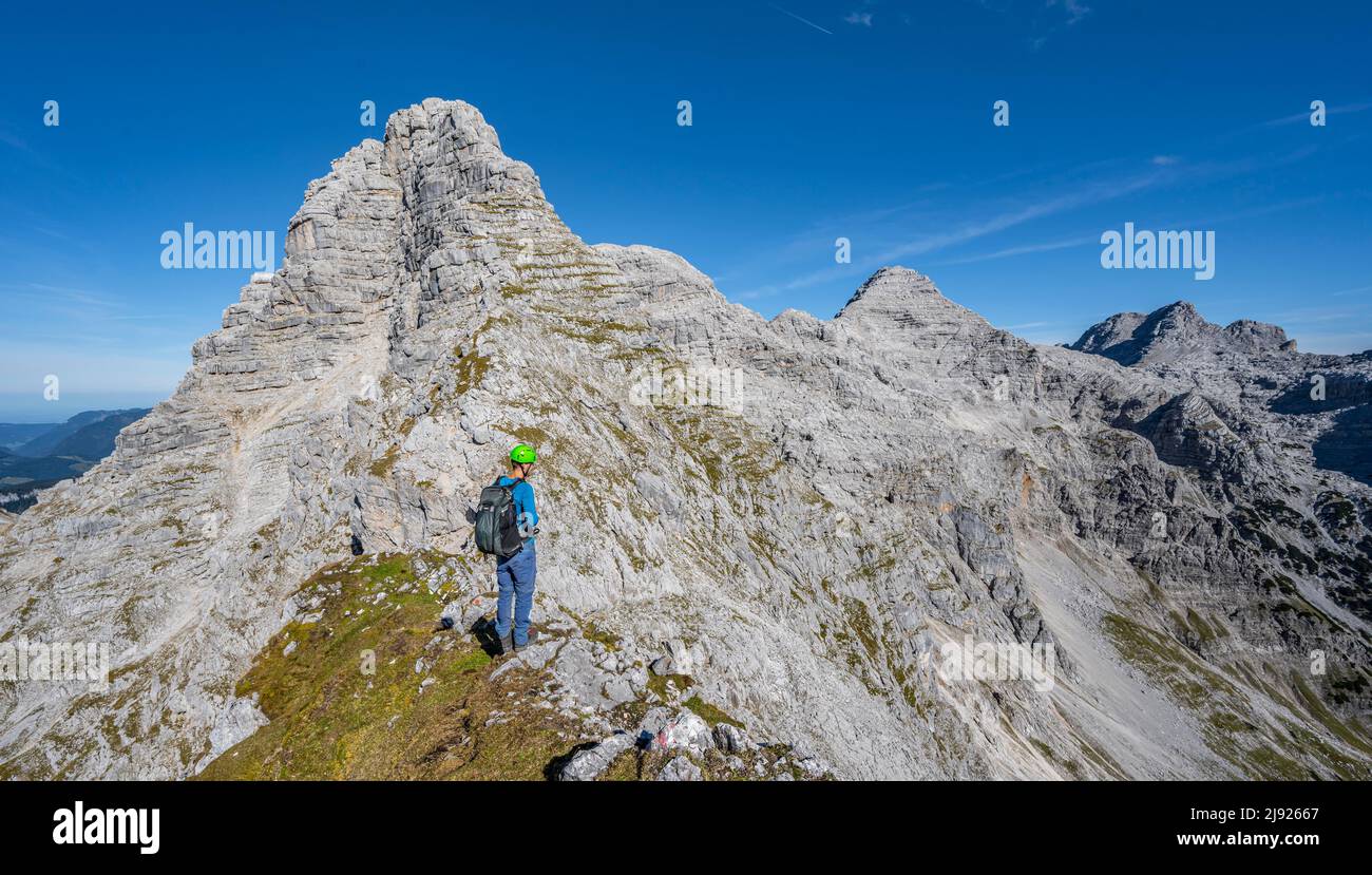 Hiker with climbing helmet, on hiking trail at a ridge, view of ...