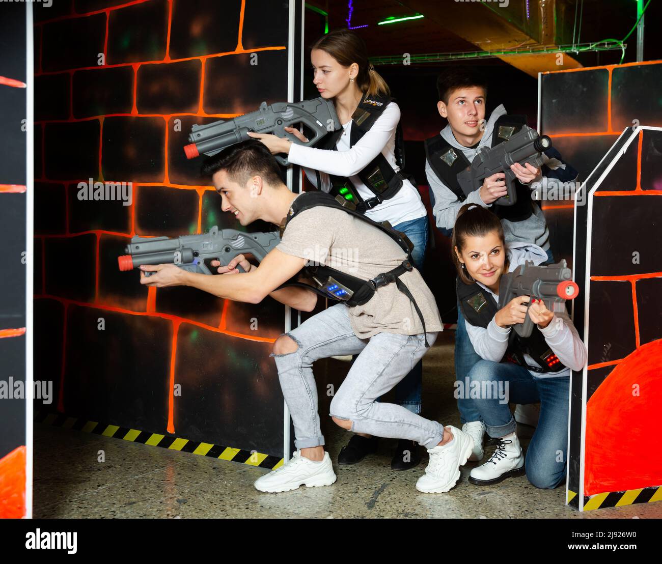 Group of young people playing laser tag game with laser guns Stock ...
