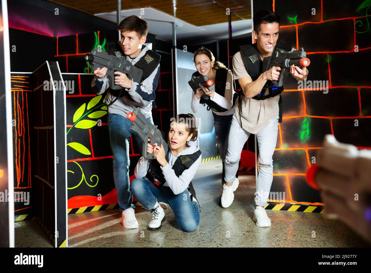 Excited young people playing enthusiastically laser tag game two teams ...