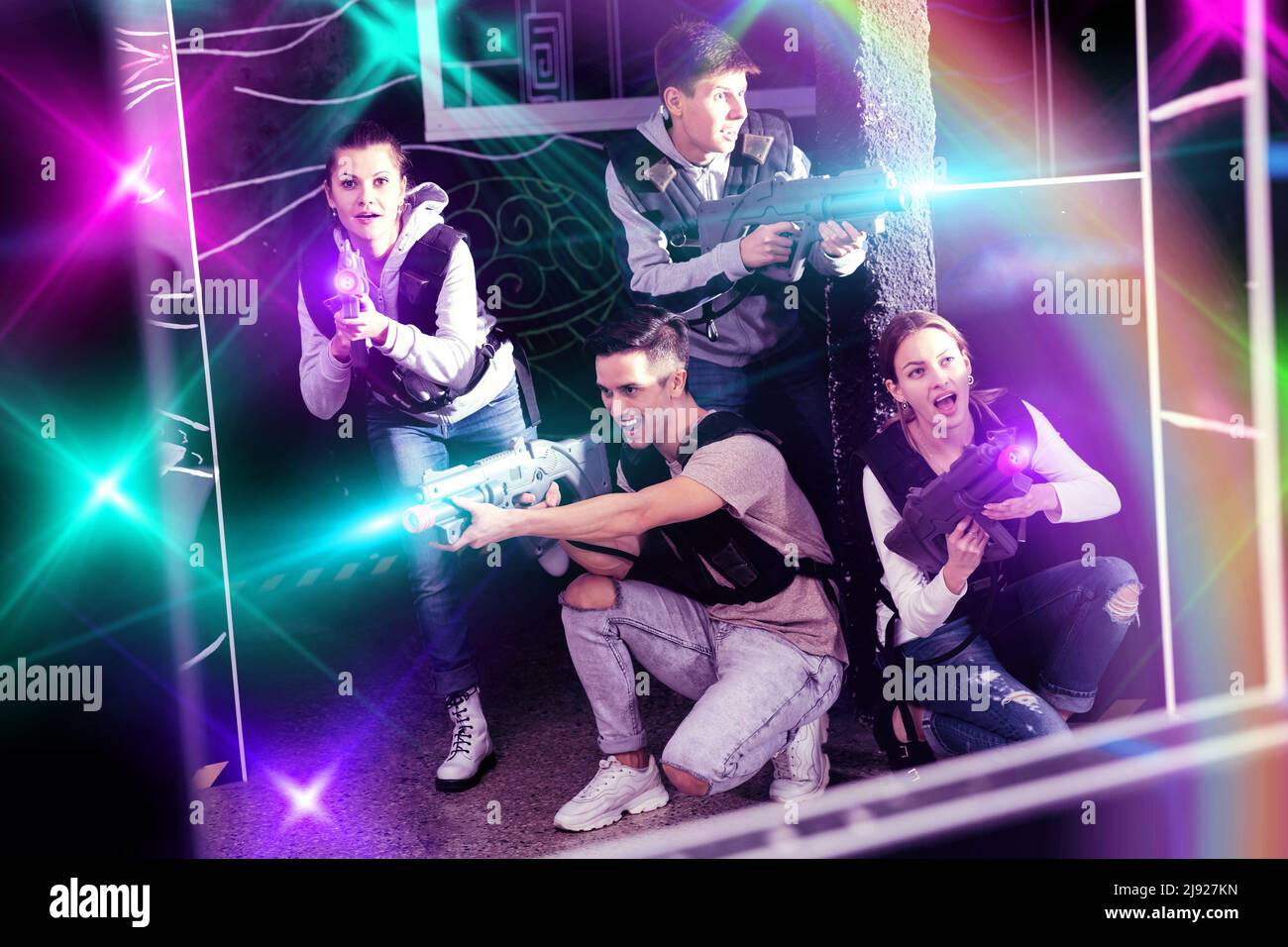 Group of adult people with laser guns having fun on dark lasertag arena ...