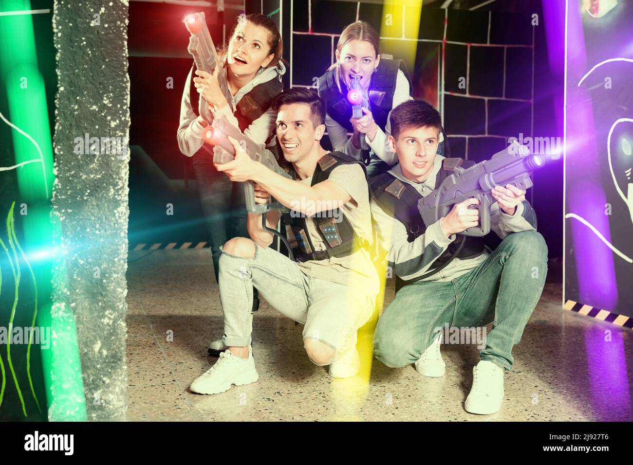 Smiling young friends playing laser tag game with colored laser Stock ...