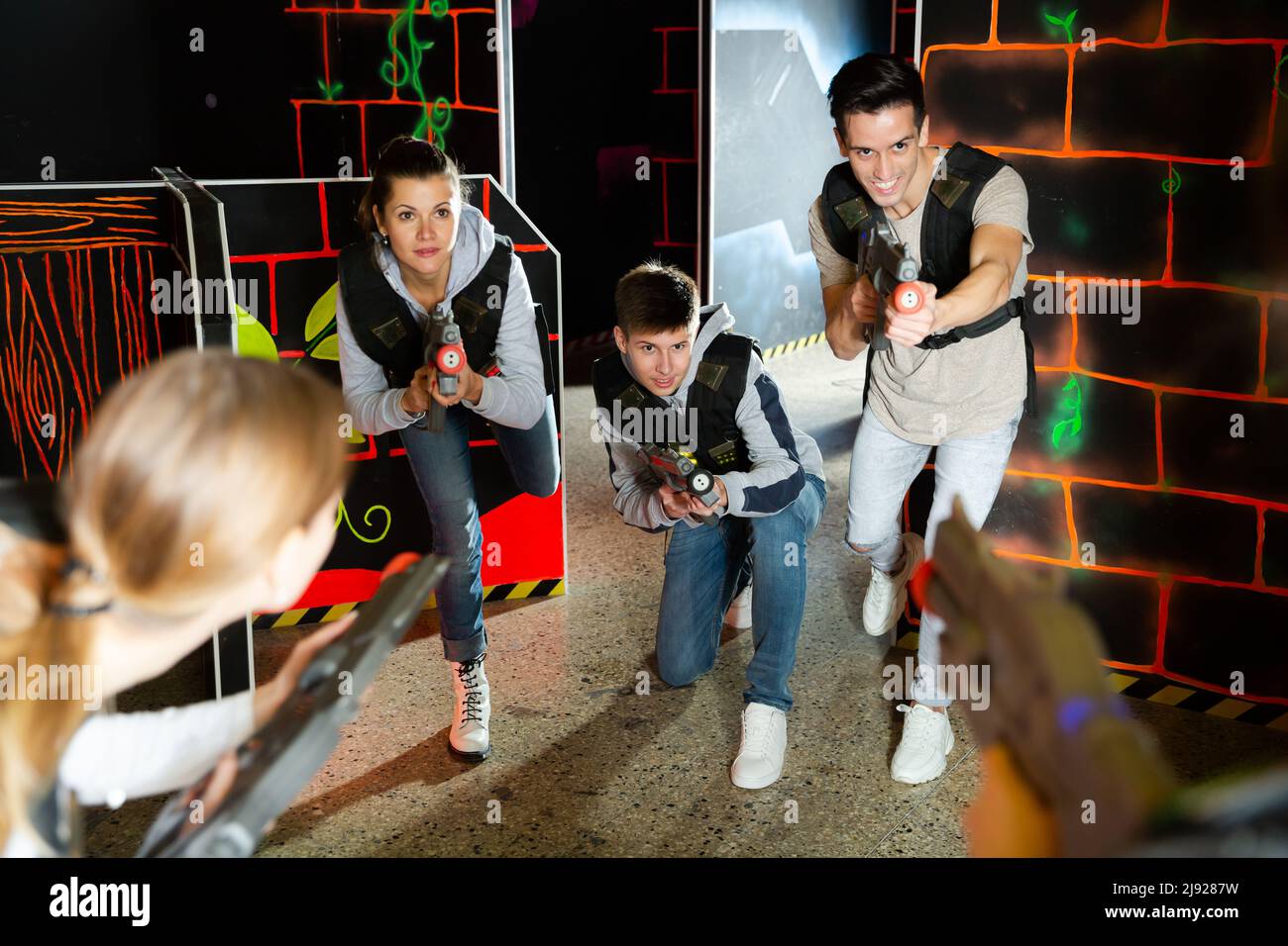 Excited young people playing enthusiastically laser tag game two teams ...