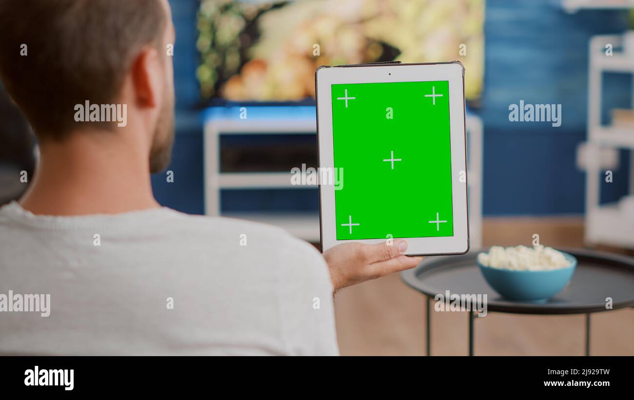 Closeup of man holding vertical digital tablet with green screen in ...