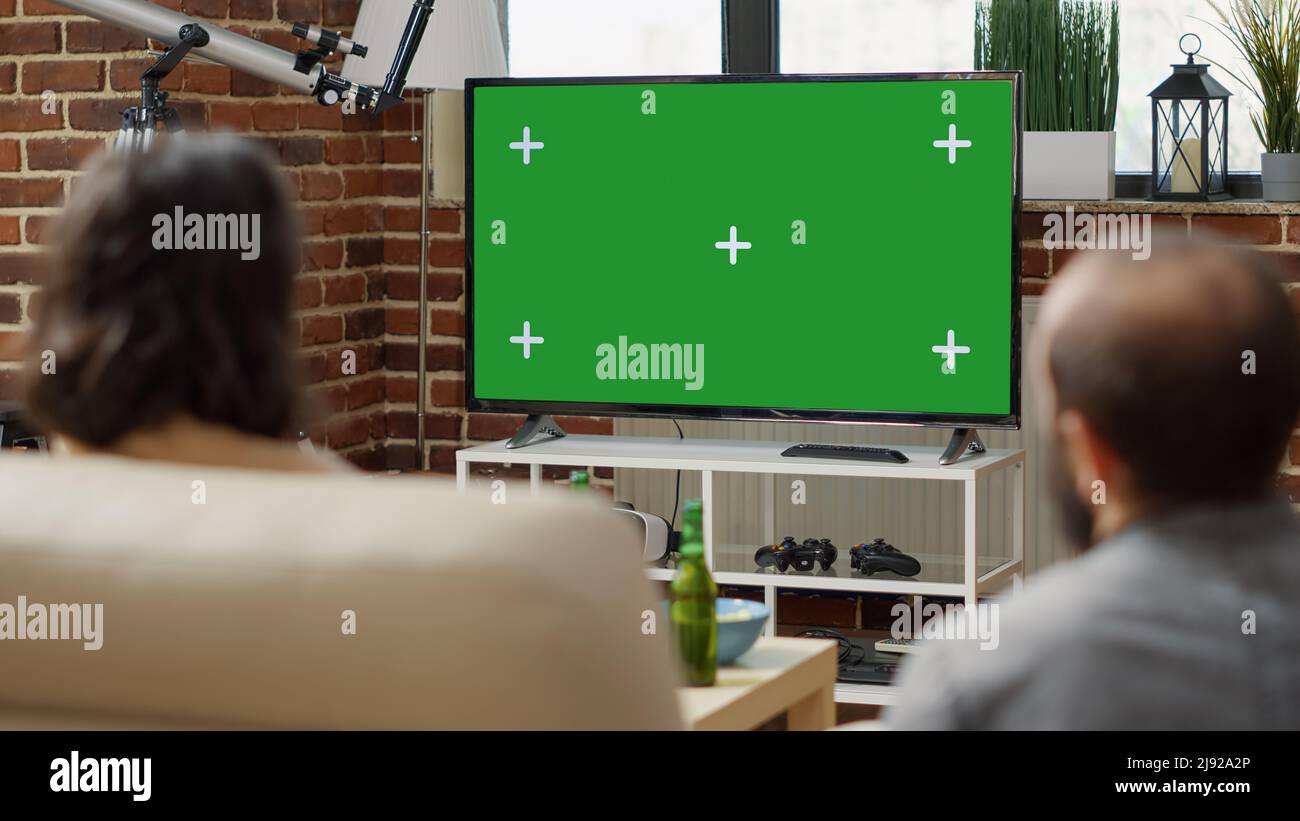Man and woman watching green screen on television display in living ...