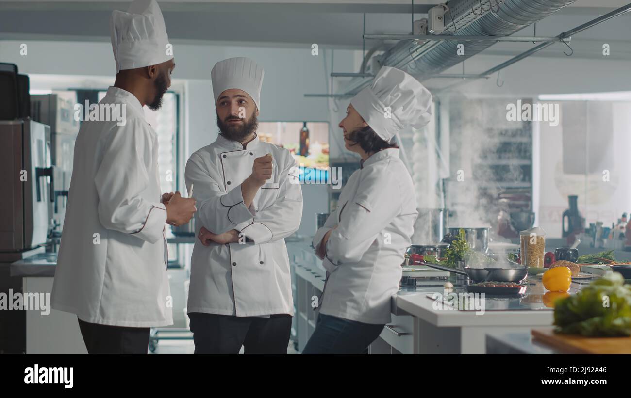 Diverse team of chefs having conversation about cooking dish ...
