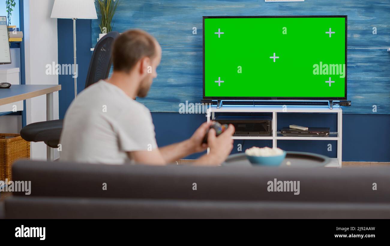 Man holding wireless controller playing console video game on green ...
