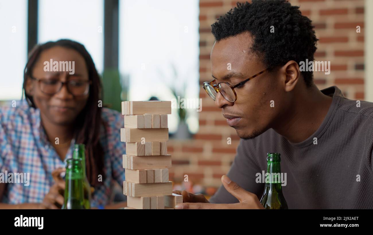 Group of cheerful people having fun with wooden tower play, enjoying ...