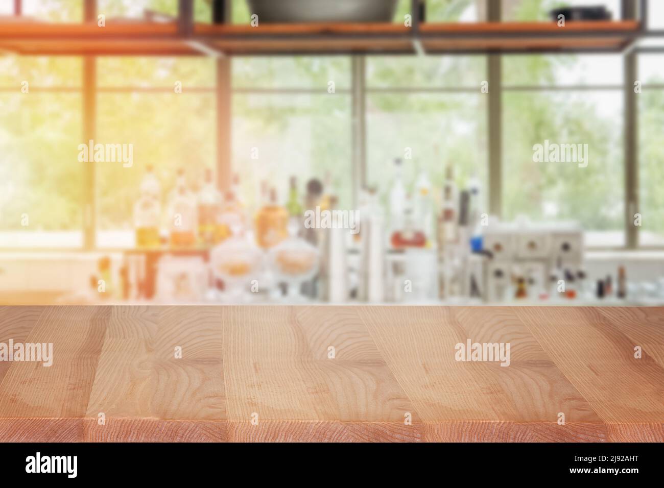 Empty wooden display table with blurred bar and bottles with alcohol on ...