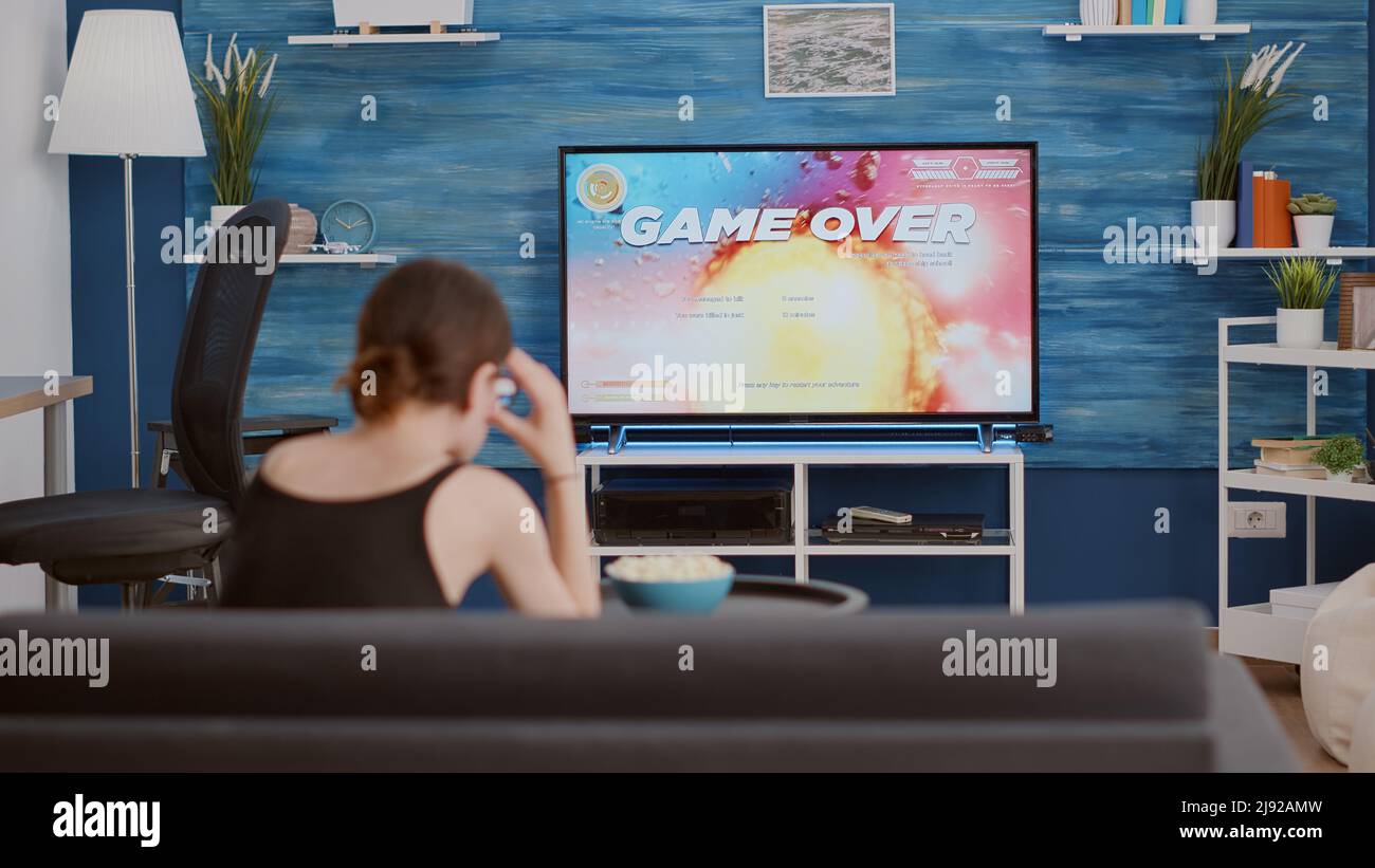 Young woman holding wireless controller playing action space shooter ...