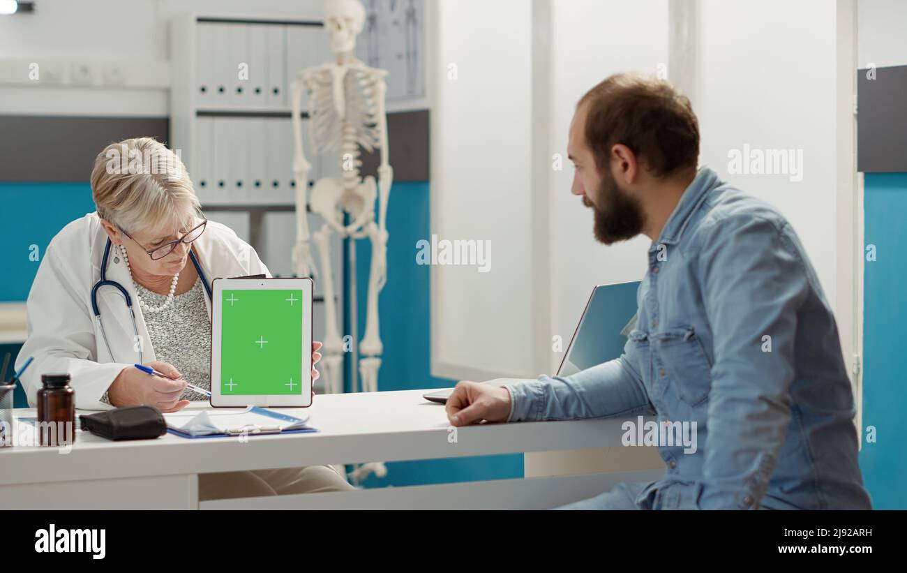 Physician and patient analyzing digital tablet with greenscreen in ...