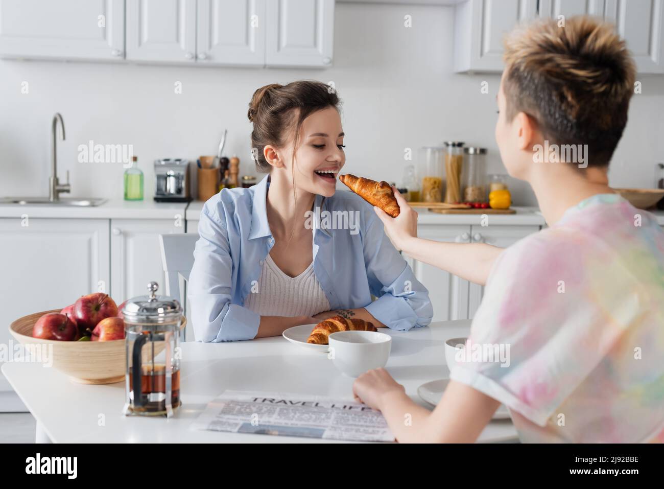 pangender person feeding partner with croissant during breakfast Stock ...