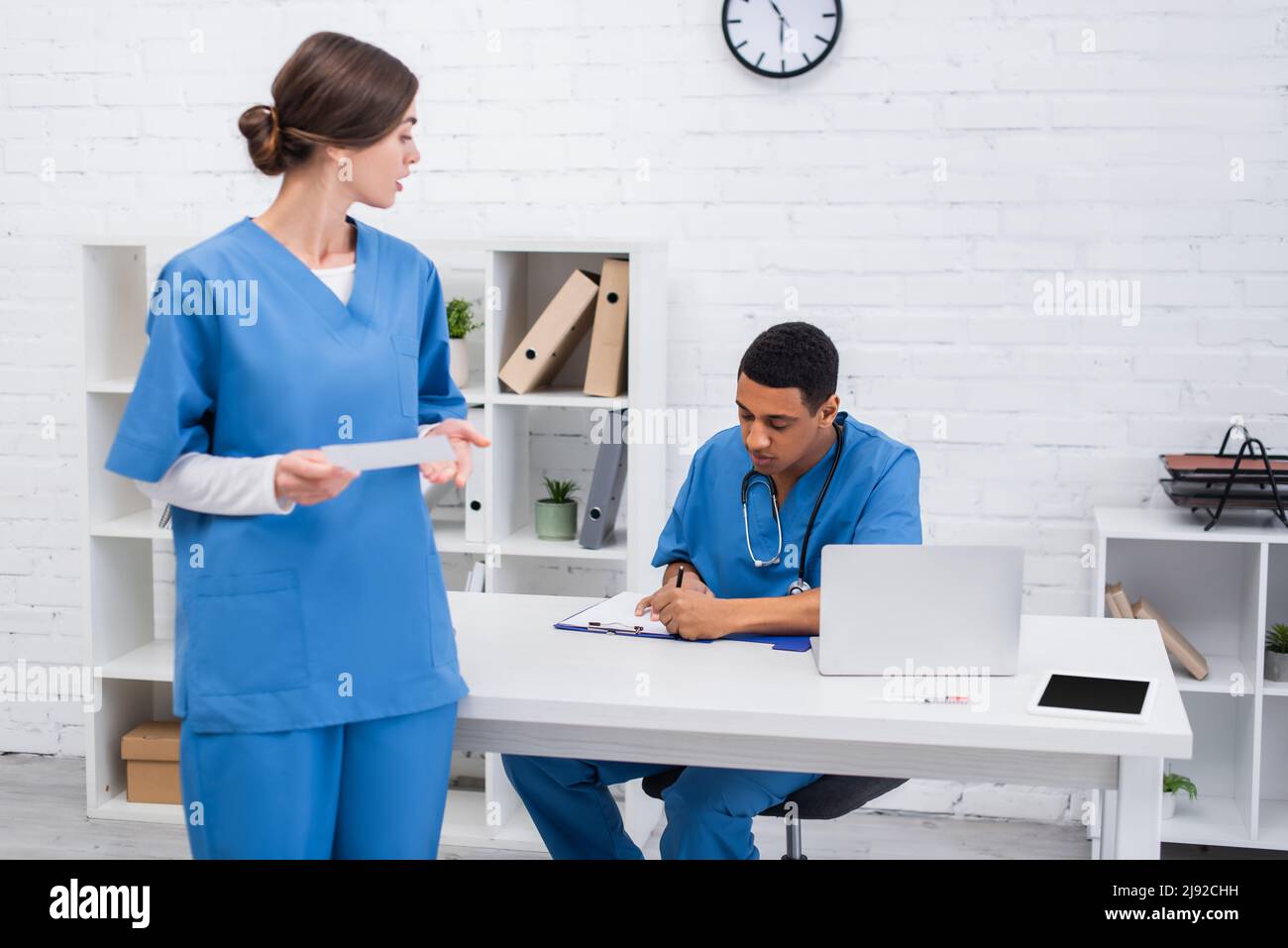 African american veterinarian writing on clipboard near colleague with ...