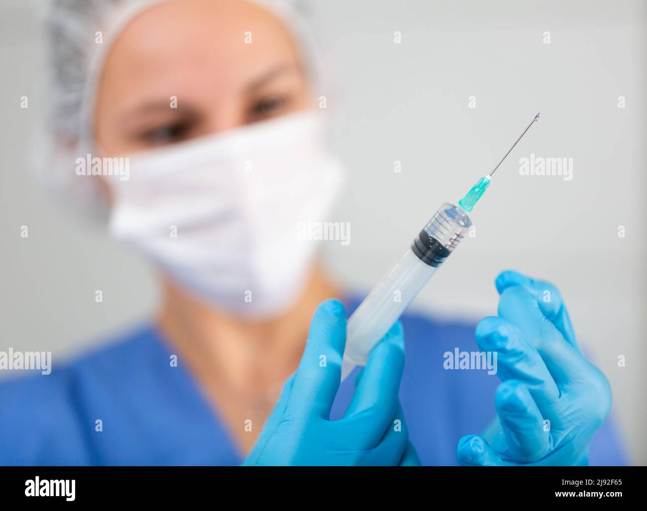 Masked female healthworker prepared a syringe for injection, filling it ...
