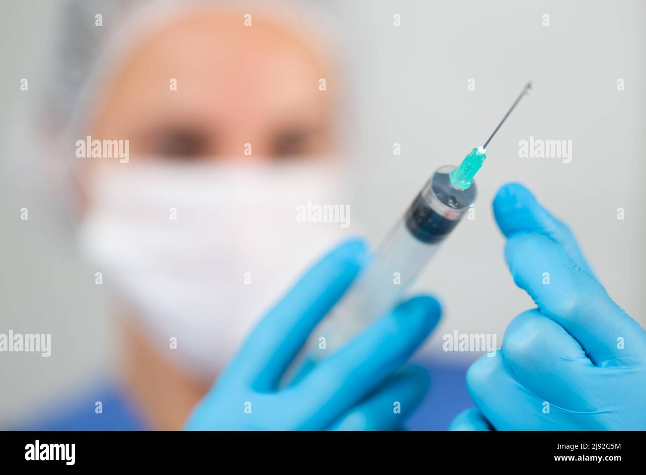 Masked female healthworker prepared a syringe for injection, filling it ...