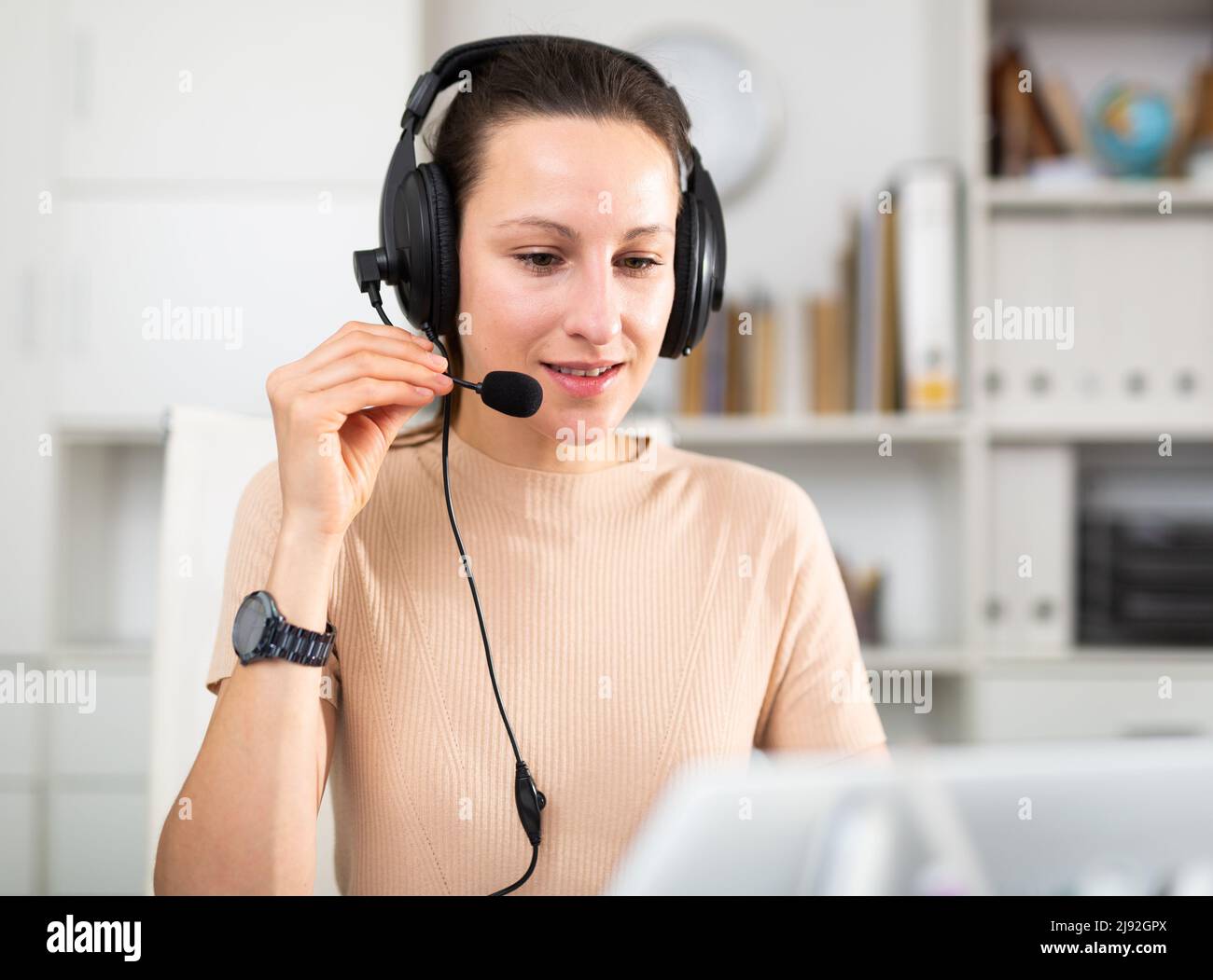 Portrait of a positive manager girl in headphones working in office ...