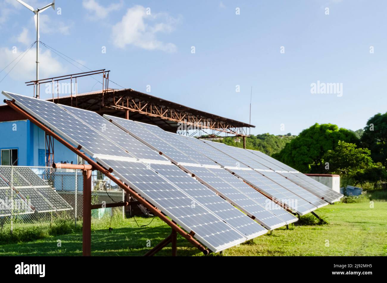 A line of solar panel placed on a metal rack outside on grass covered ...