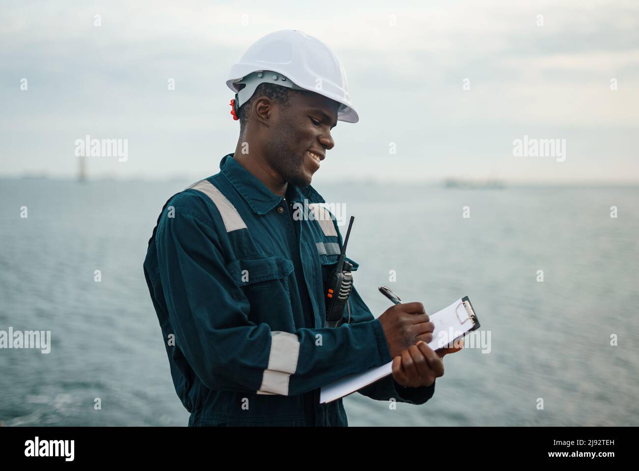 Black seaman writing down data on clipboard Stock Photo - Alamy