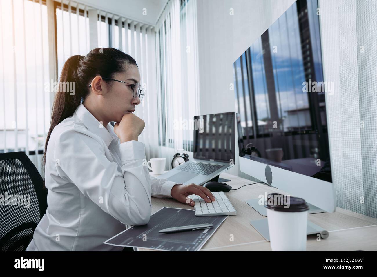 Asian female software developer is worried about analyzing code-based systems at his office ...