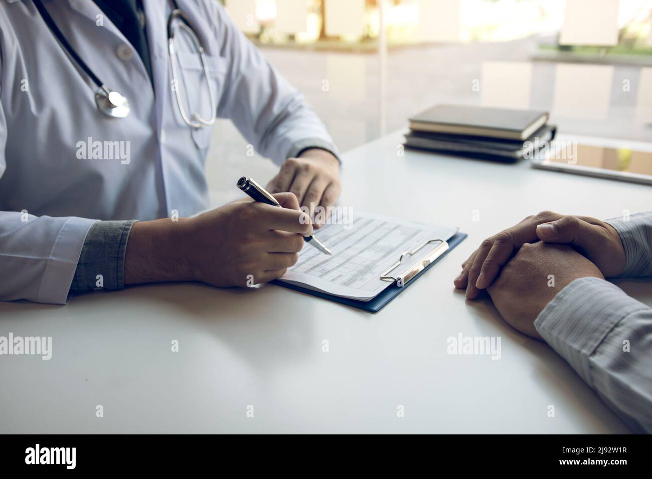 Doctor hand holding pen and talking to the patient about medication and ...