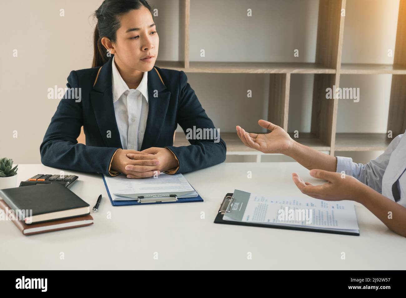 Asian young adult sitting at desk across from manager being interviewed ...