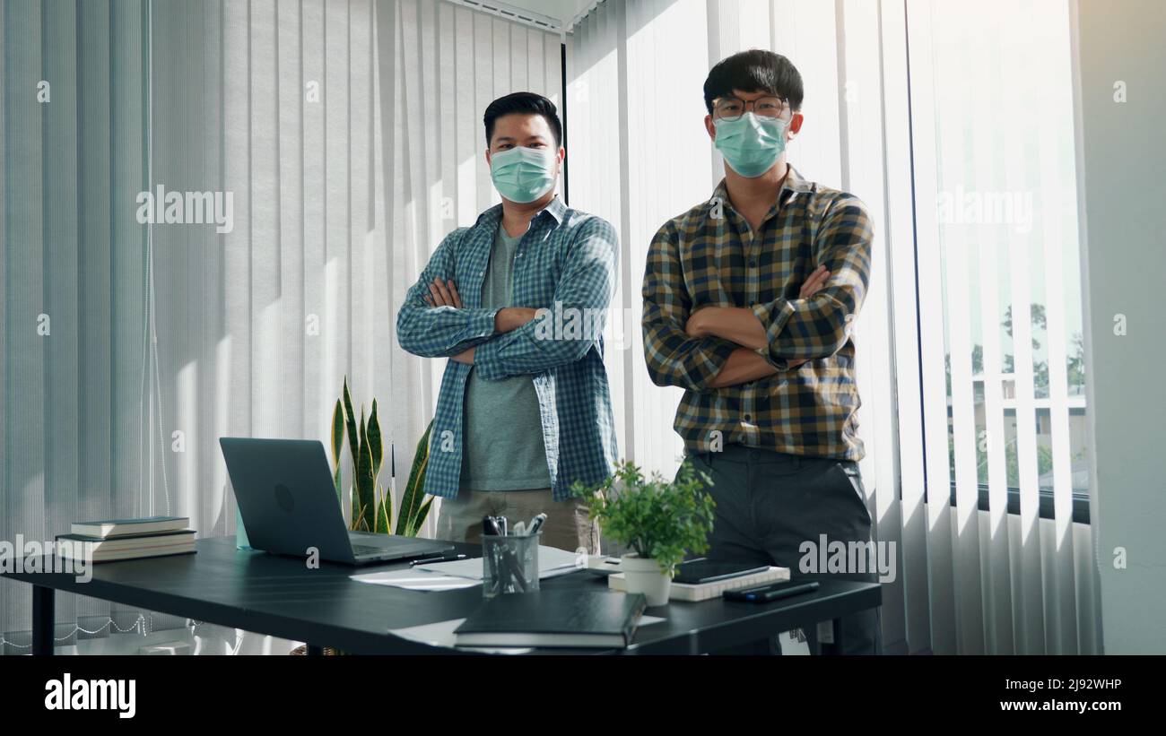 Asian colleagues are standing with arms folded, expressing confidence ...