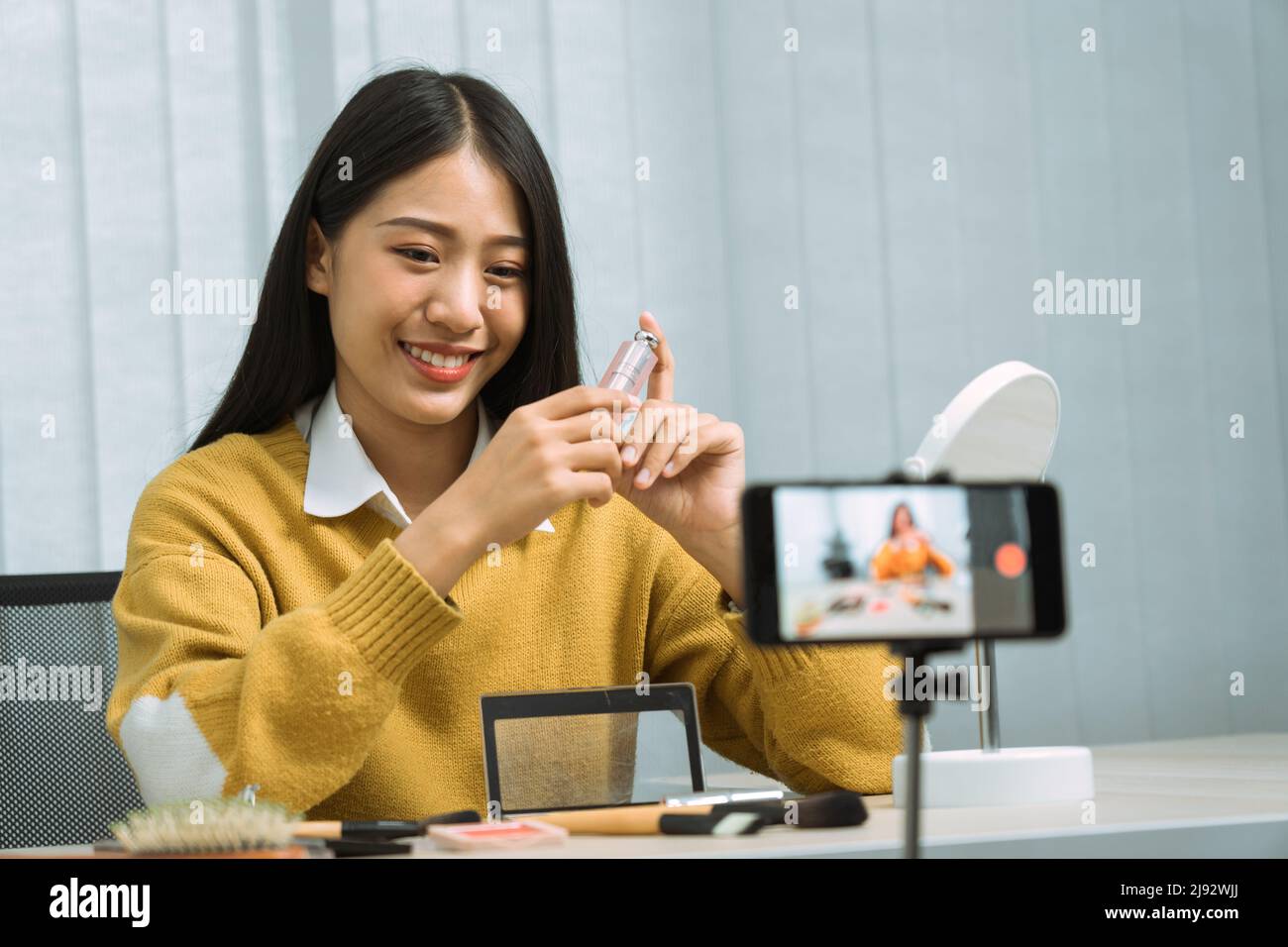 Young asian woman vlogging about cosmetics skin care items products on ...