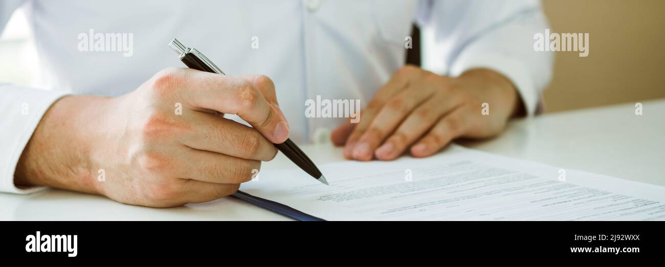 Doctor hand holding pen writing patient history list on note pad and ...