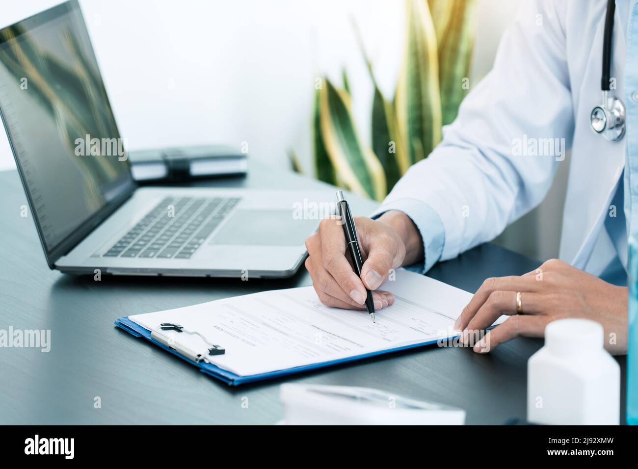Doctor hand holding pen writing patient history list on clipboard about ...