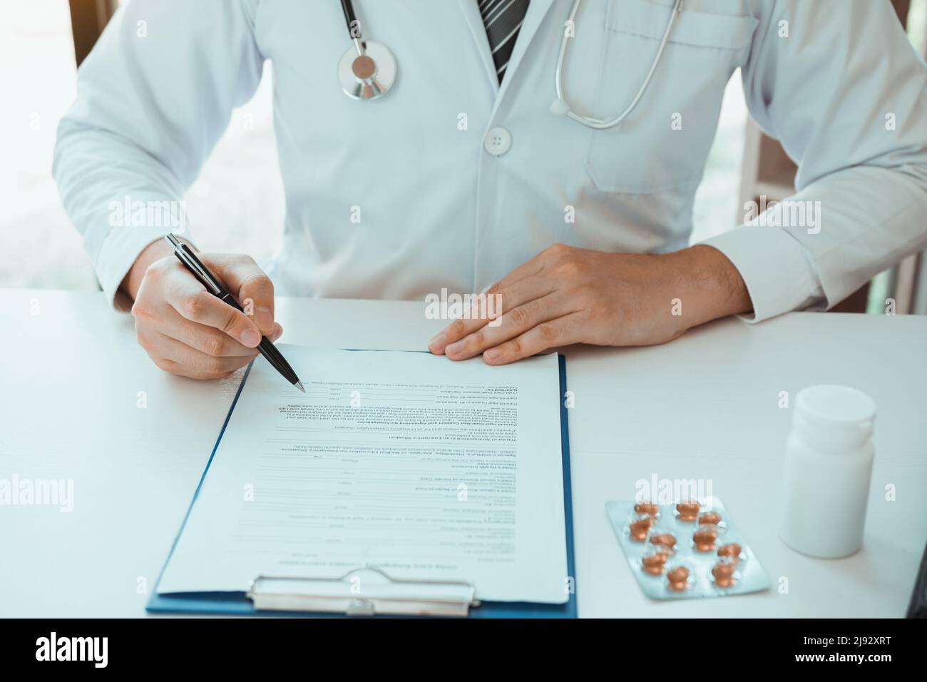 Doctor hand holding pen writing patient history list on note pad and ...