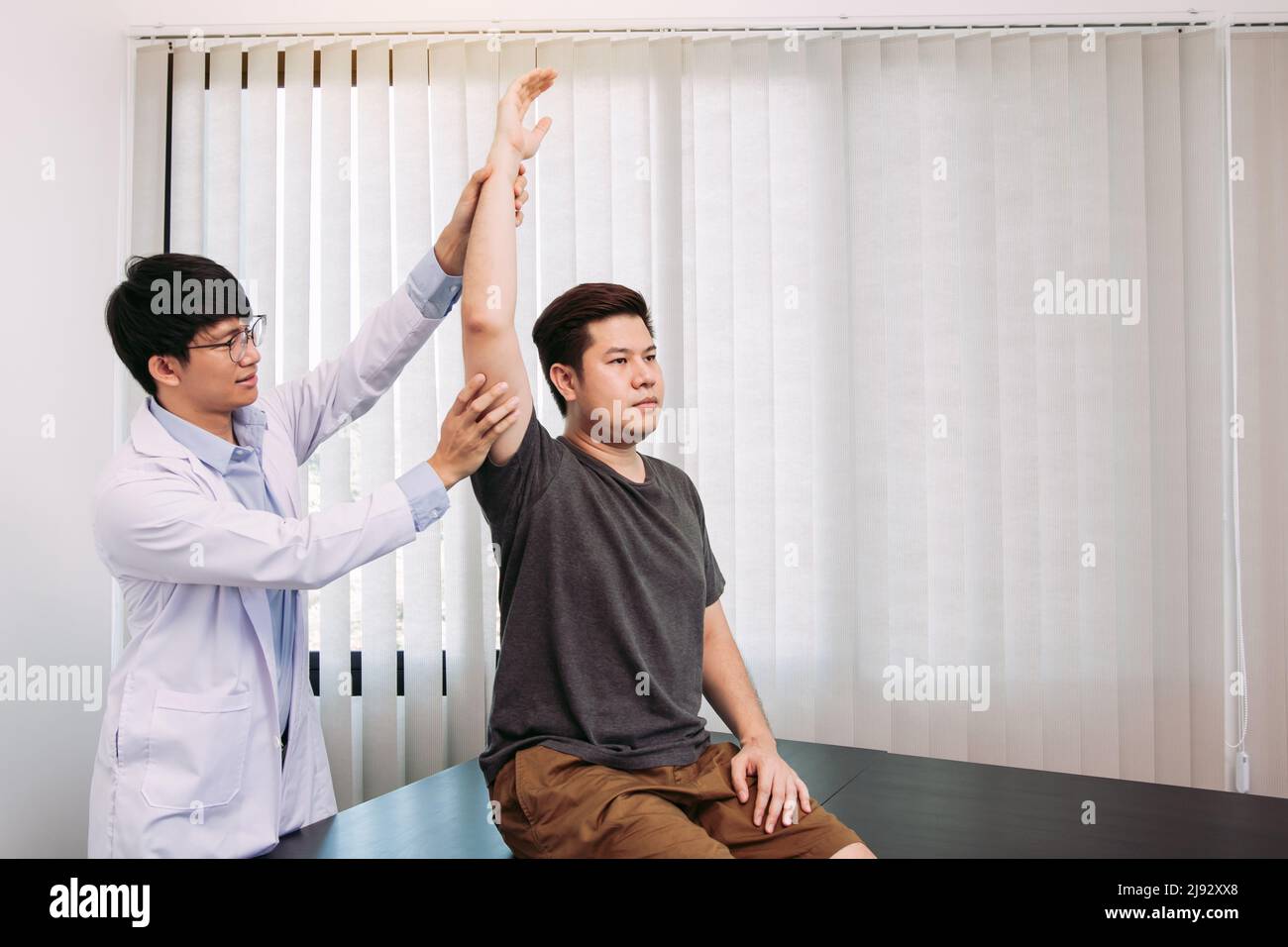 Chiropractor stretching a young man arm in medical office Stock Photo ...