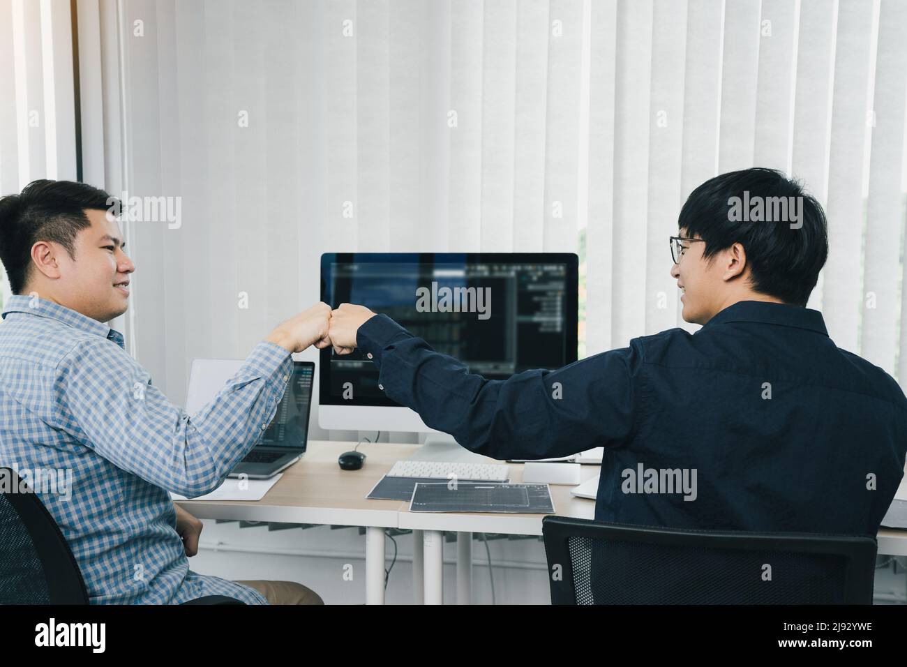 Asian employee software developers celebrate success project by fist bump in office room Stock ...