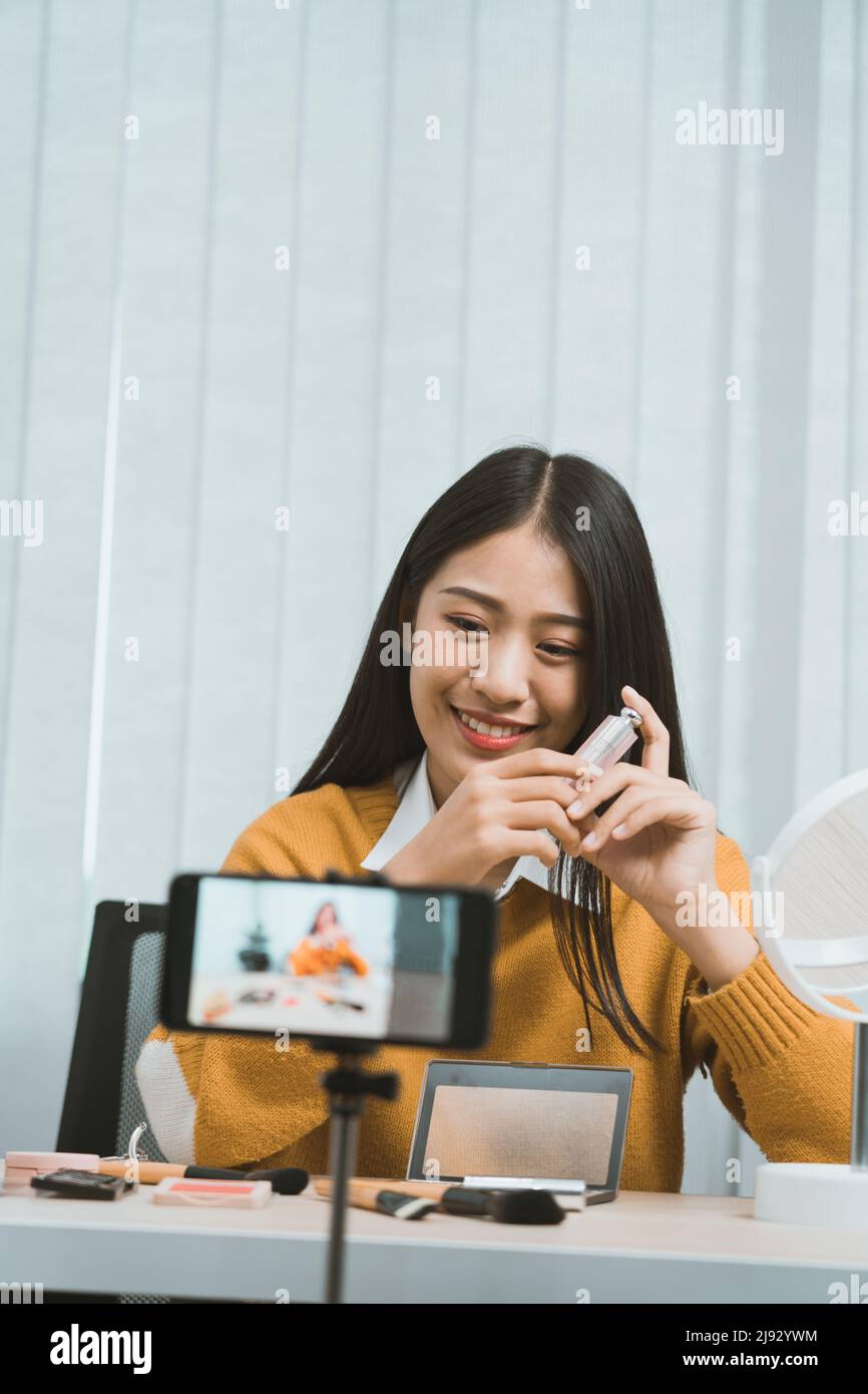 Young asian woman vlogging about cosmetics skin care items products on ...